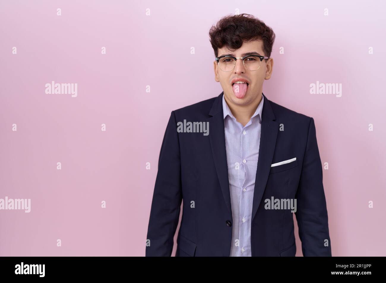 Young non binary man with beard wearing suit and tie sticking tongue ...