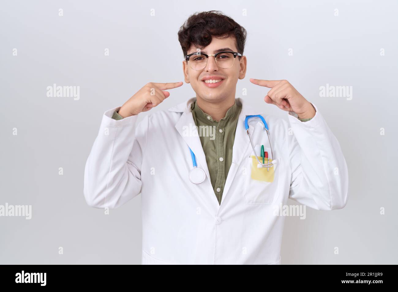 Young non binary man wearing doctor uniform and stethoscope smiling ...