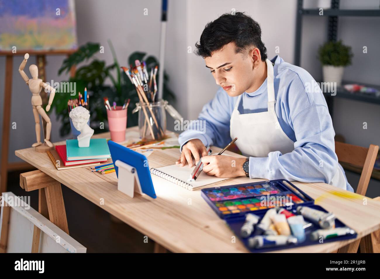 Young non binary man artist using touchpad drawing on notebook at art ...