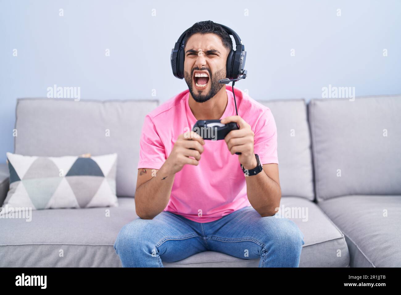 Hispanic young man playing video game holding controller sitting on the ...