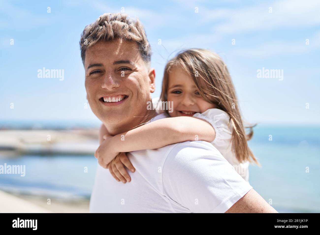 Father and daughter smiling confident hugging each other holding on back at seaside Stock Photo ...