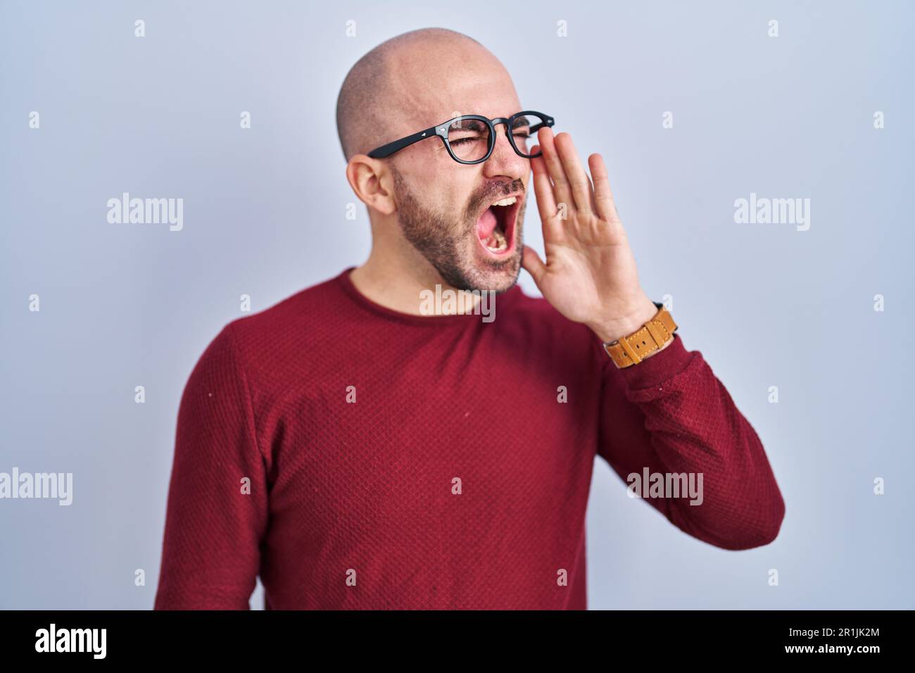 Young bald man with beard standing over white background wearing ...