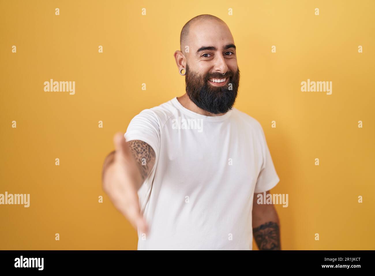 Young hispanic man with beard and tattoos standing over yellow ...