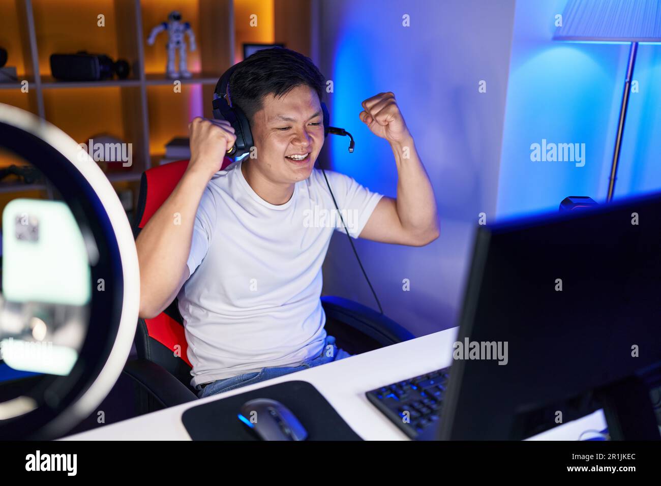 Young chinese man streamer playing video game with winner expression at ...