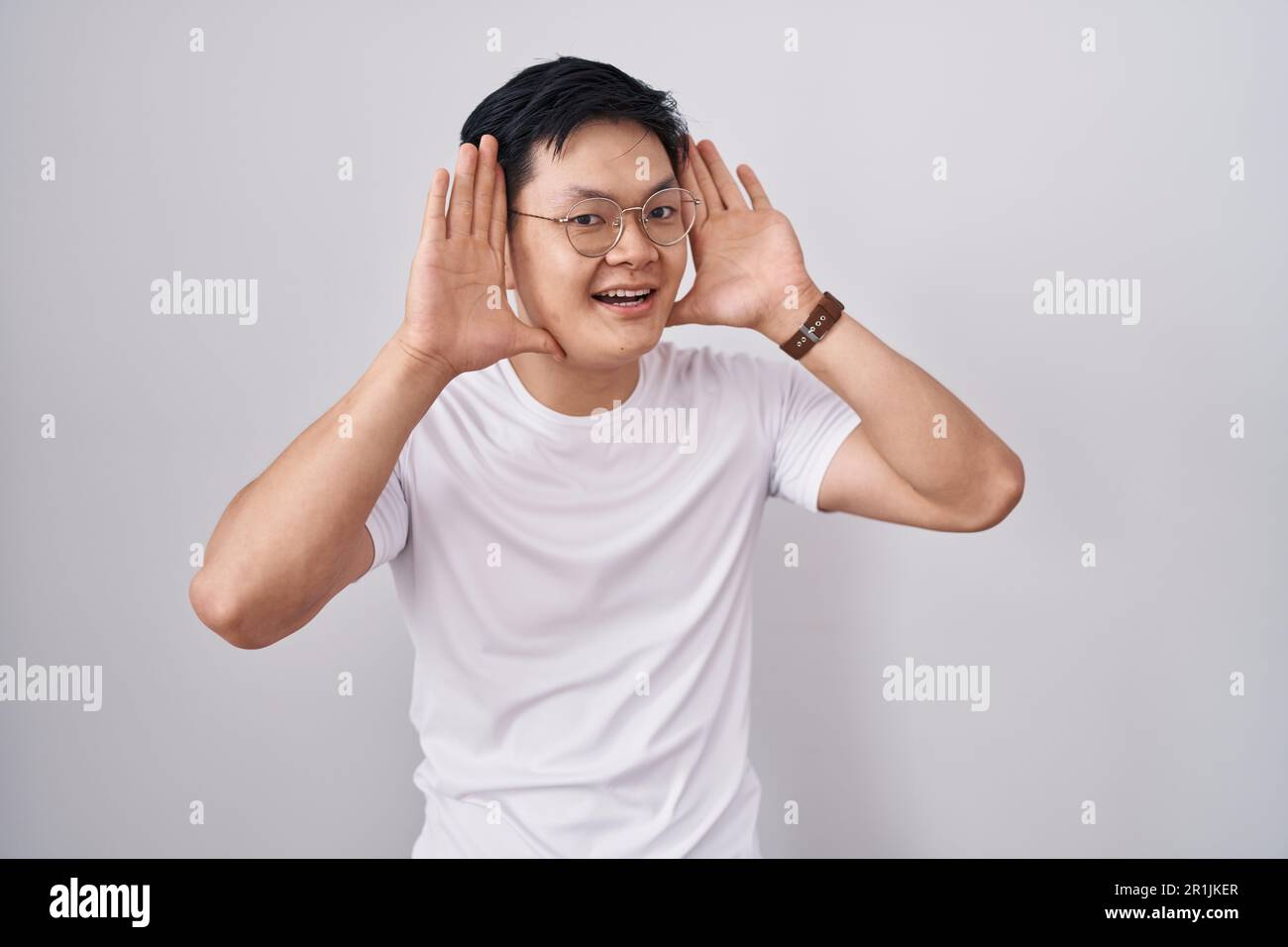 Young asian man standing over white background smiling cheerful playing ...