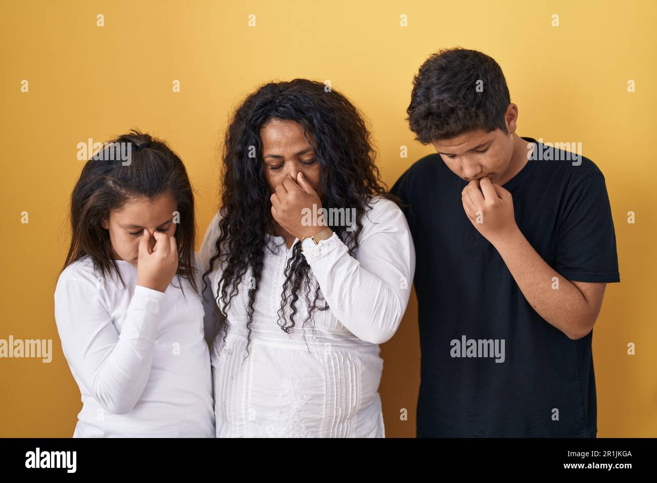 Family of mother, daughter and son standing over yellow background ...
