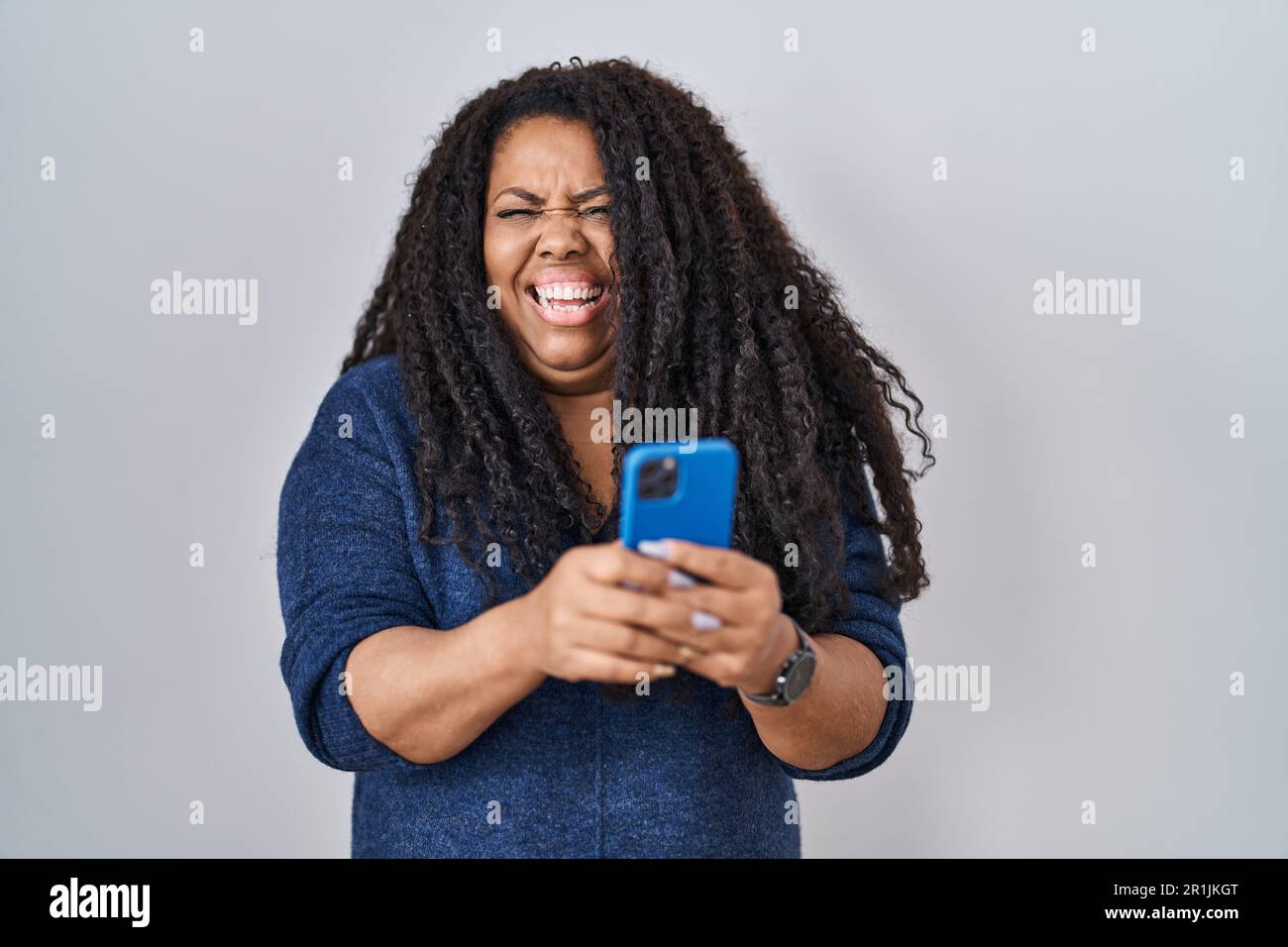 Plus size hispanic woman using smartphone typing message celebrating ...