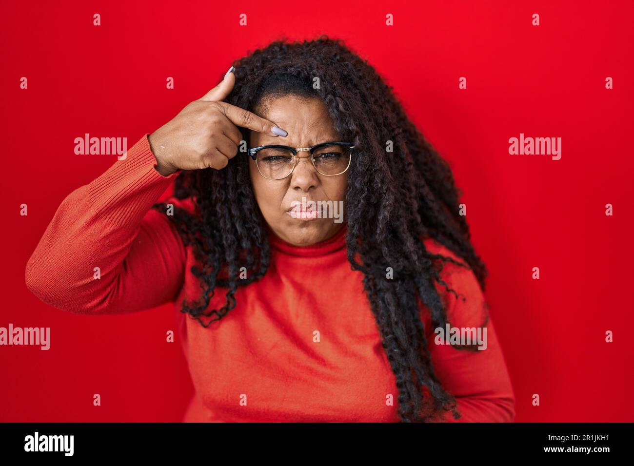 Plus size hispanic woman standing over red background pointing unhappy ...