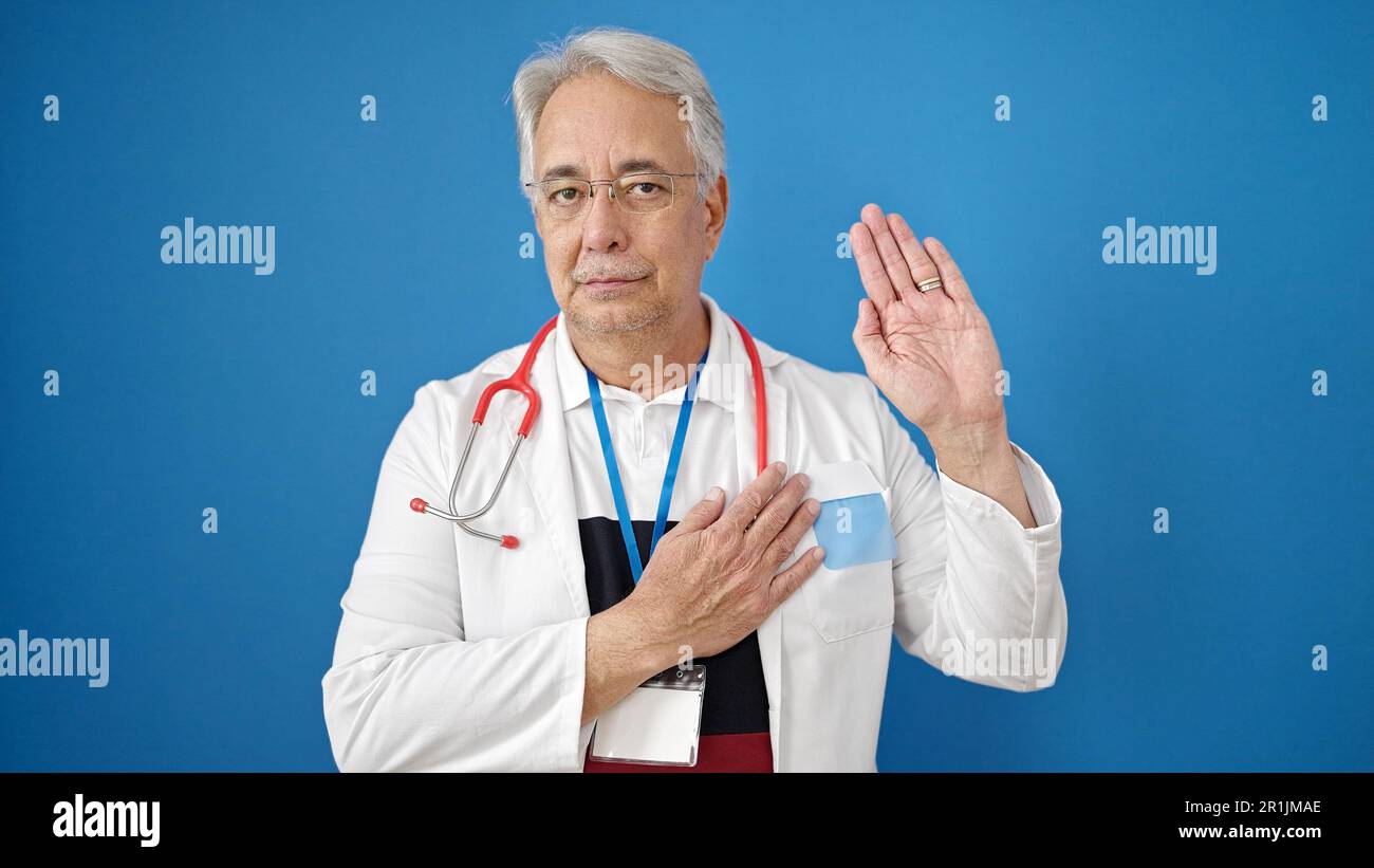 Middle age man with grey hair doctor making an oath with hand on chest ...