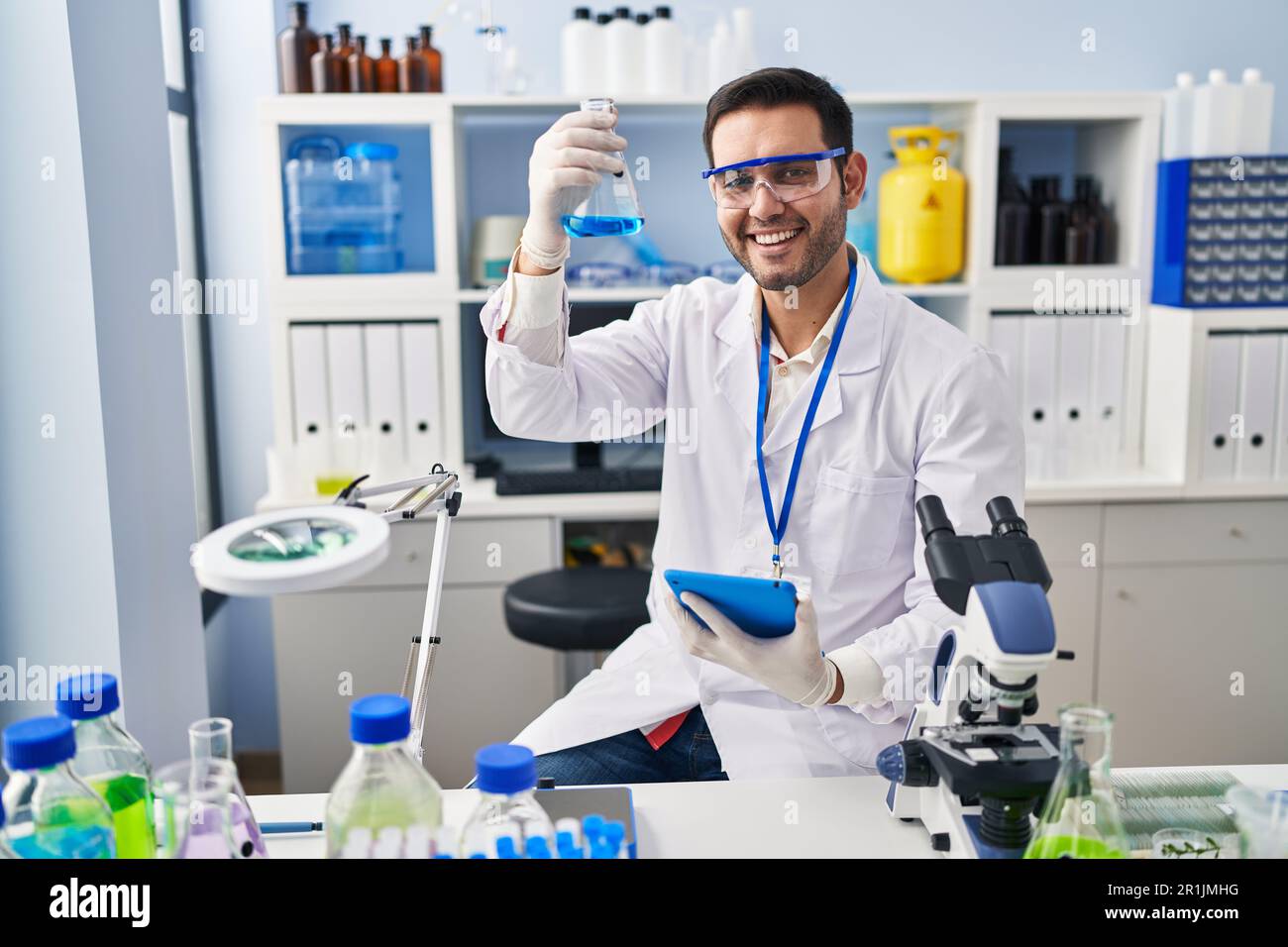 Young hispanic man scientist measuring liquid using touchpad at laboratory Stock Photo - Alamy