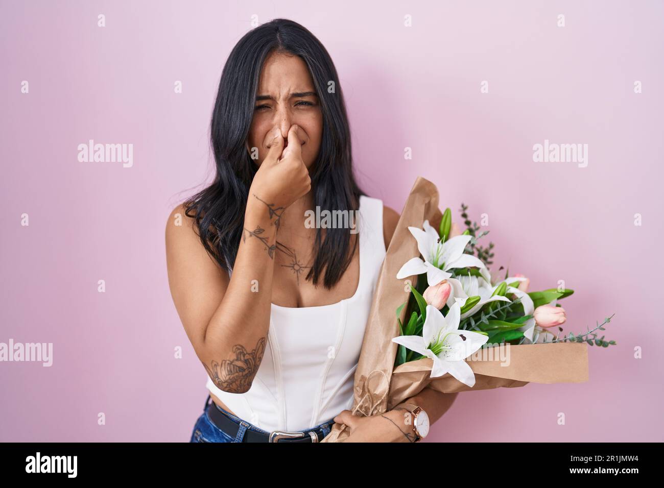 Brunette woman holding bouquet of white flowers smelling something ...