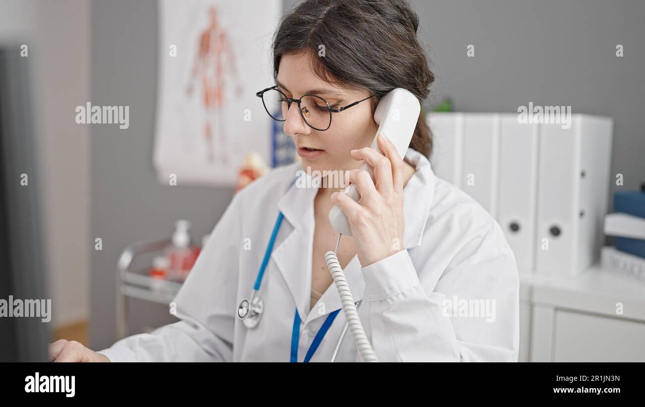Young beautiful hispanic woman doctor using computer talking on ...
