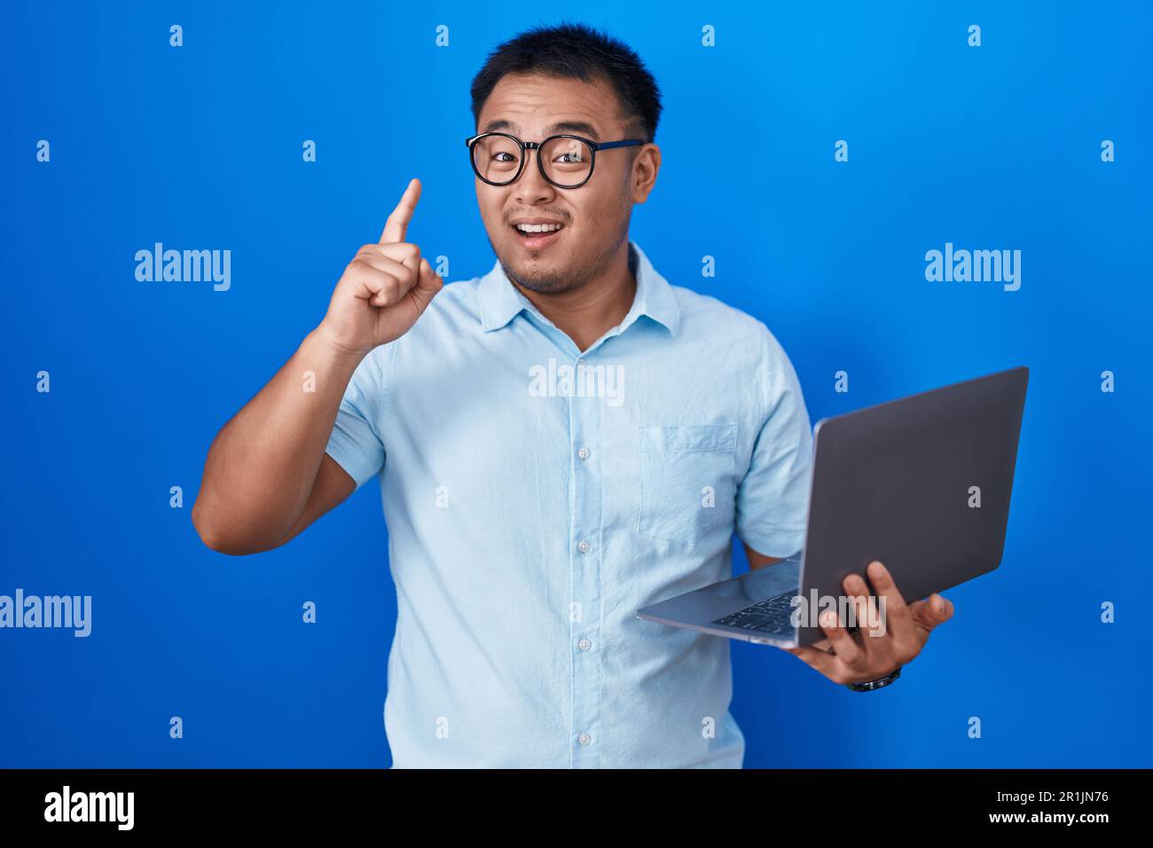Chinese young man using computer laptop pointing finger up with ...