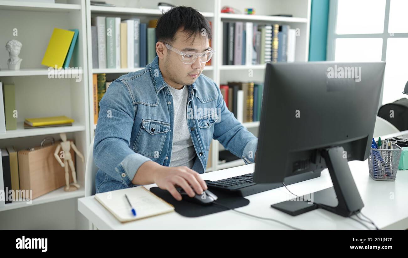 Young chinese man student using computer studying at library university ...