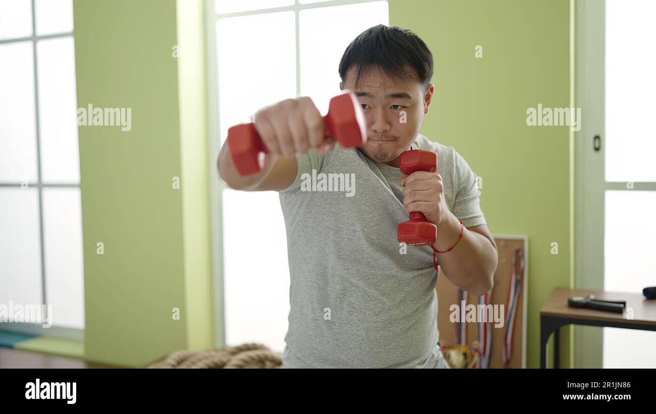 Young chinese man using dumbbells boxing at sport center Stock Photo ...