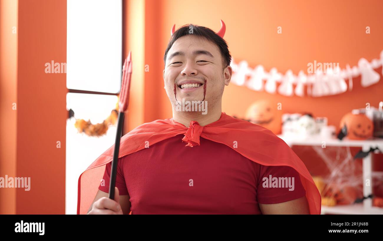 Young chinese man wearing devil costume holding trident at home Stock ...