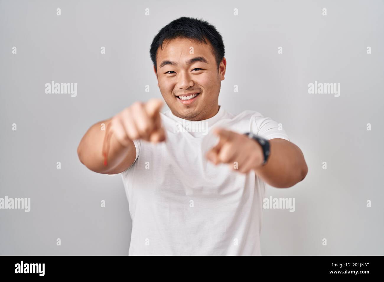 Young chinese man standing over white background pointing to you and ...