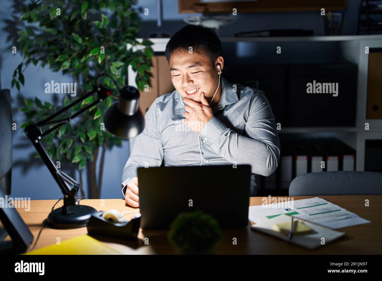 Young chinese man working using computer laptop at night looking ...