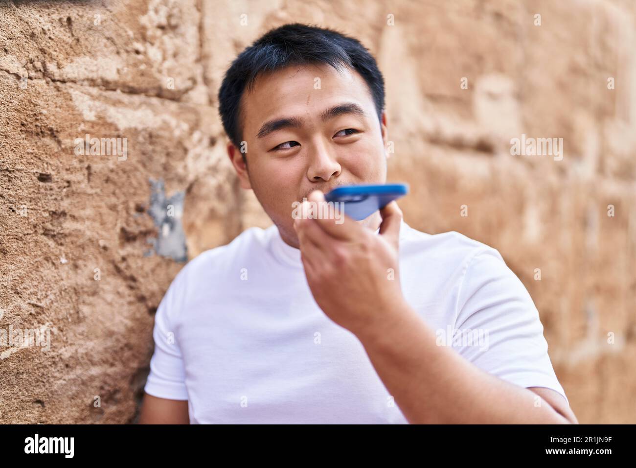 Young chinese man smiling confident talking on the smartphone at street ...