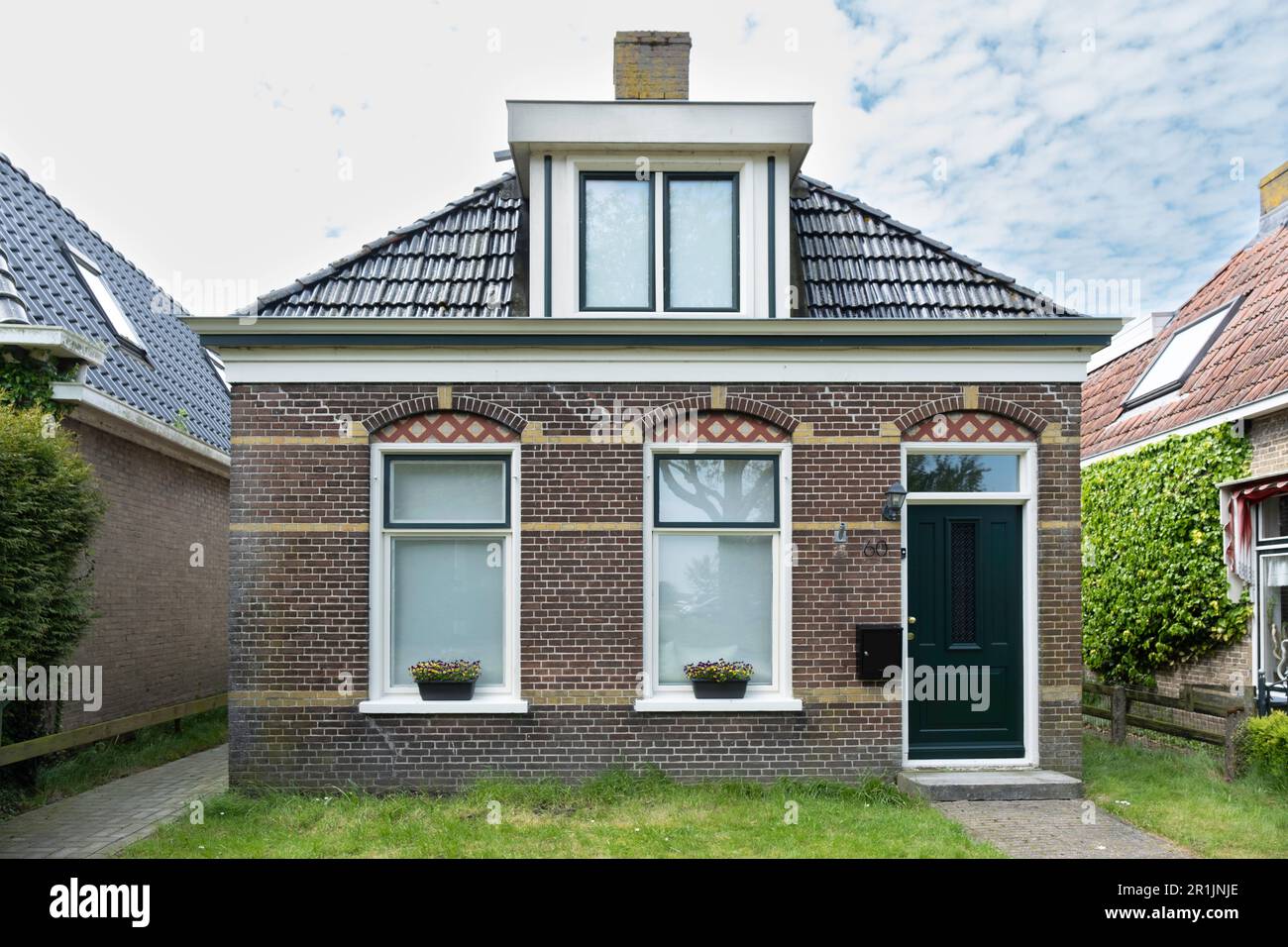 Facade of a very small detached brick house with dormer, windows and ...