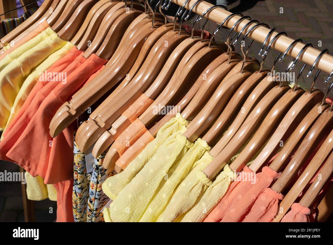 Cheap colorful summer dresses hang back to back in the sun on wooden ...