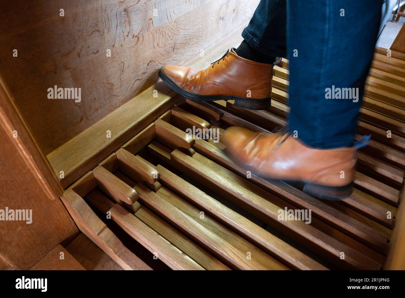 Musician pushes his feet on the pedals of the organ in a church. Motion ...