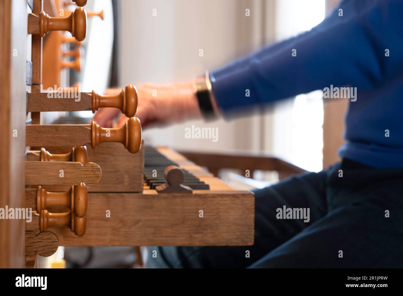 Hands of an organist playing a church organ. Seen from the side, narrow ...