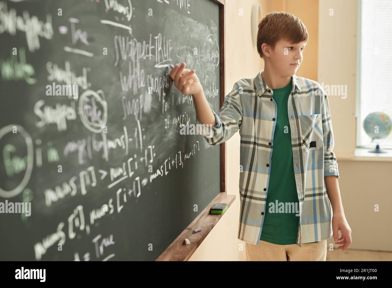 Side view portrait of teen schoolboy answering in class by blackboard ...
