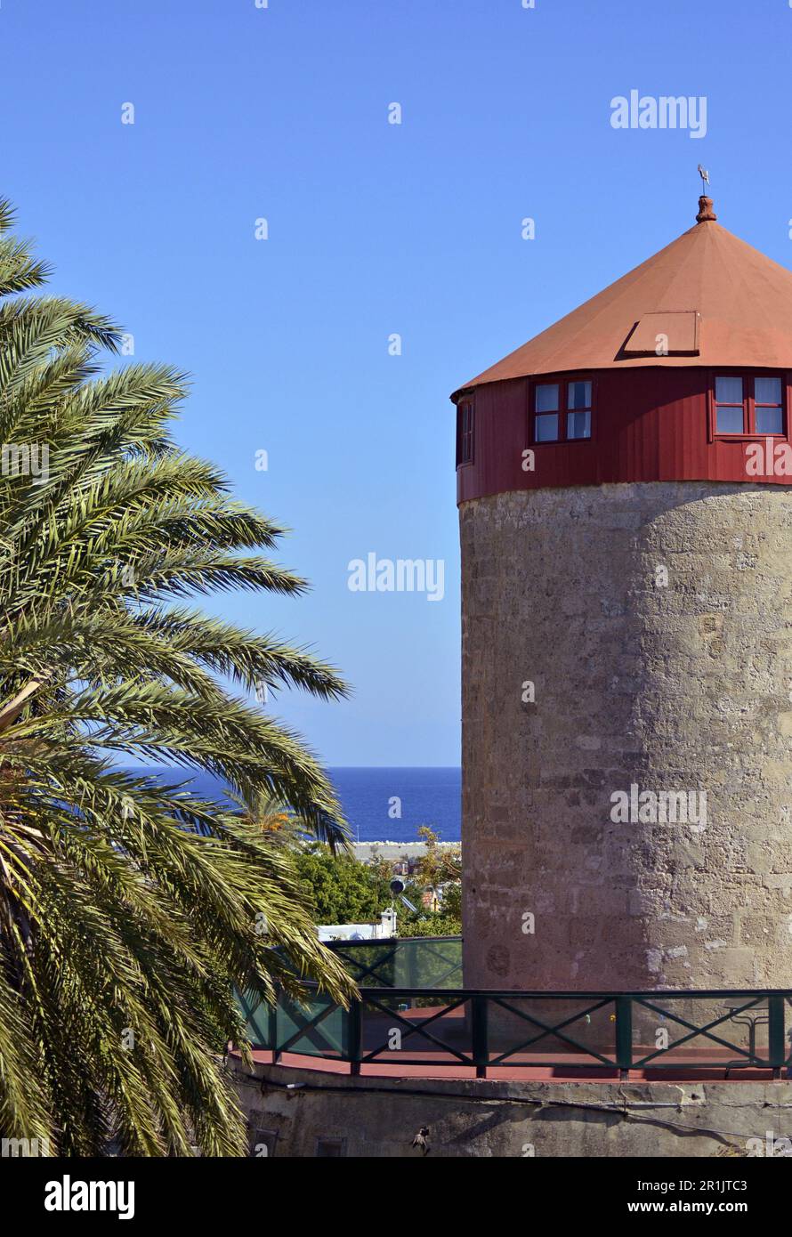 Medieval mill tower with a red stone roof. A tower and a palm tree with ...