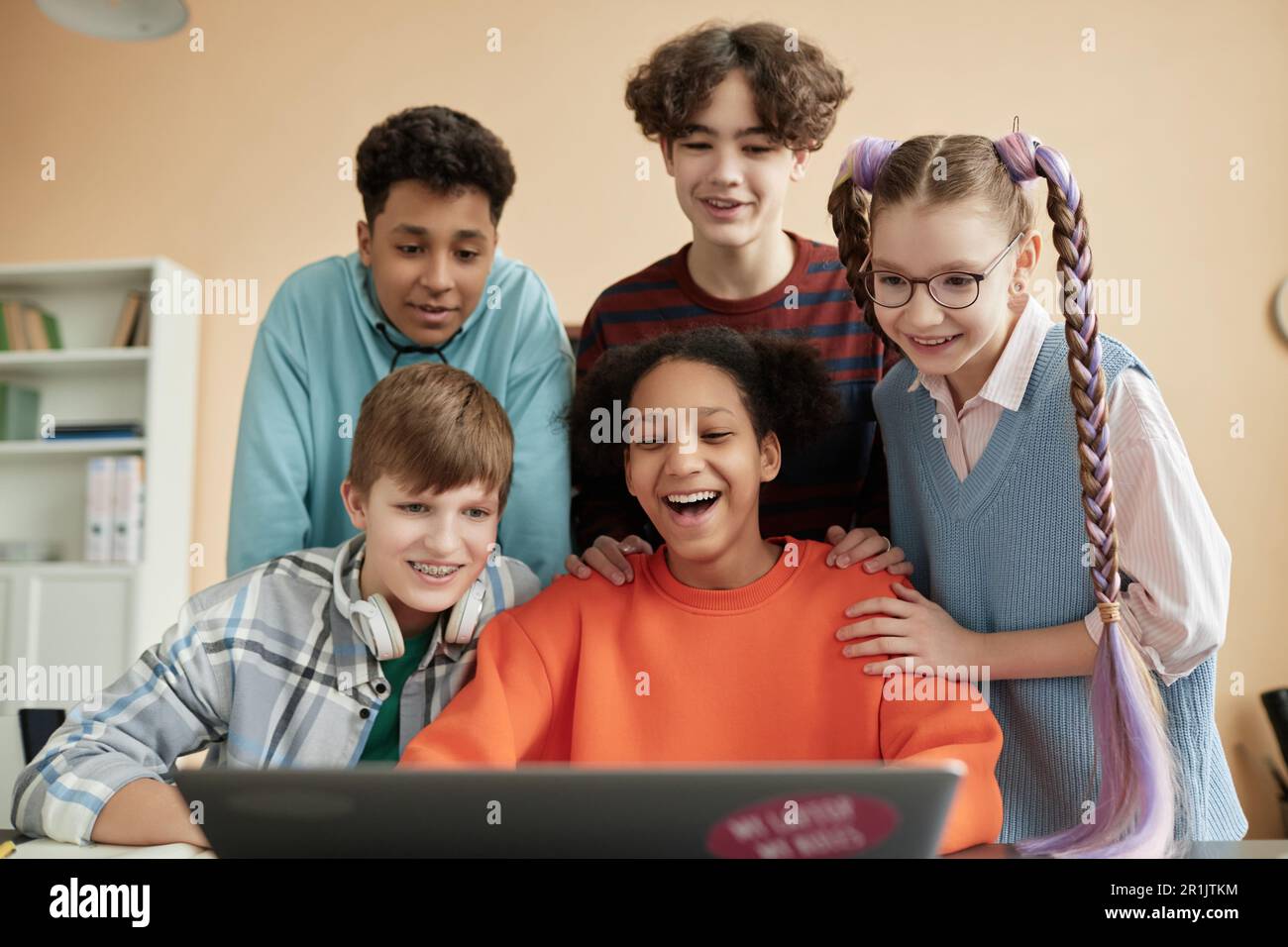 Group of cheerful school children using laptop computer in class during ...