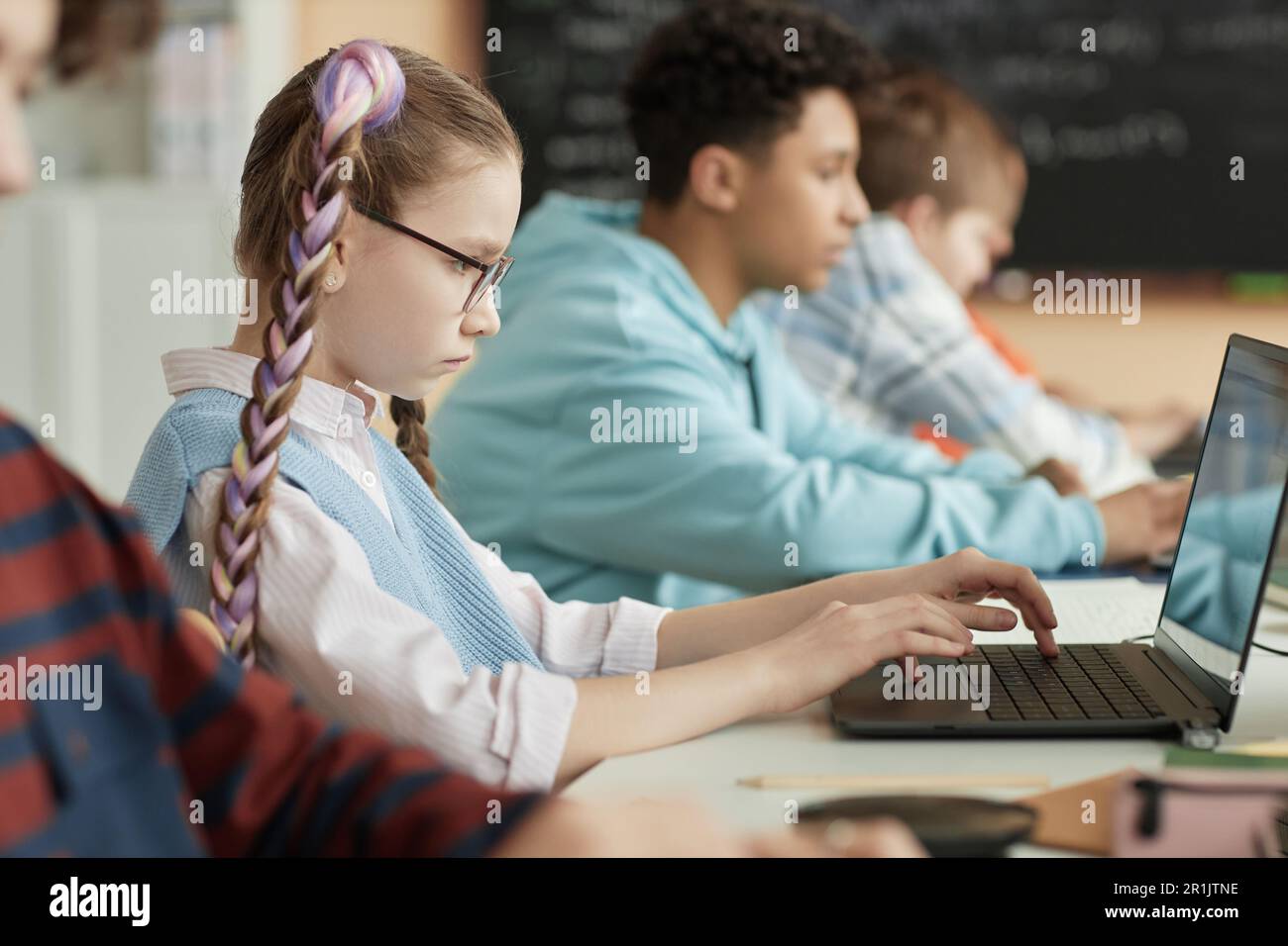 Side view at school children using computers in row and taking online ...