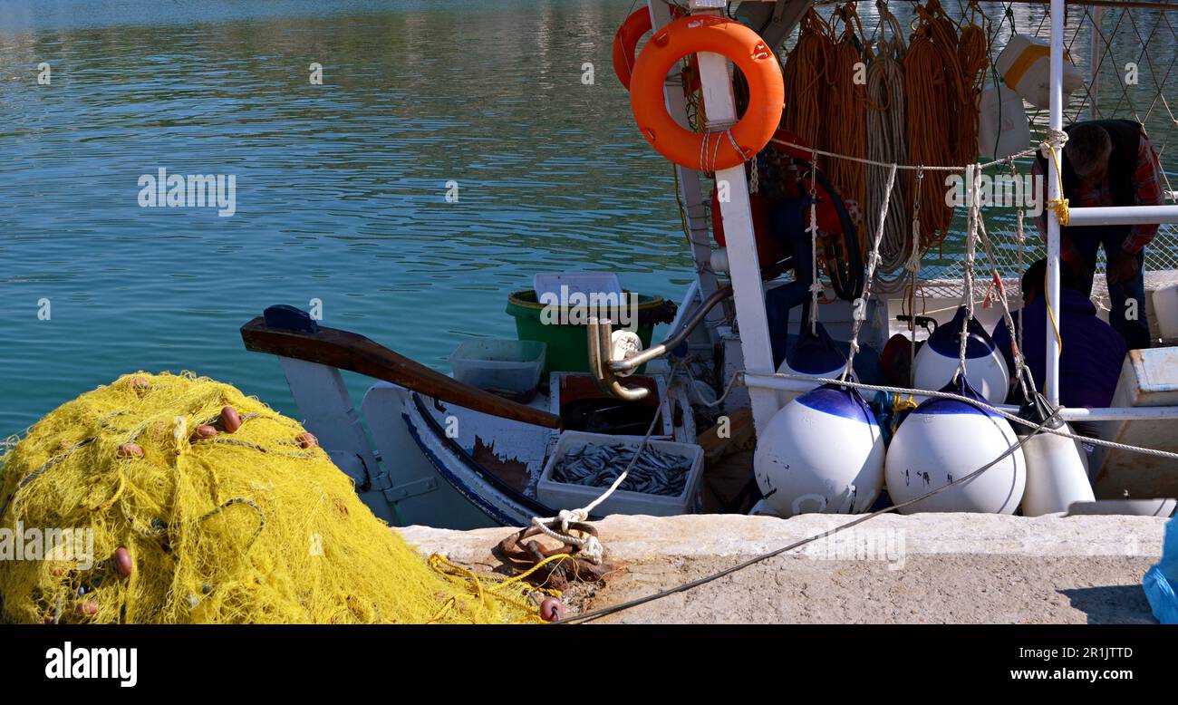 A fishing boat with a canopy and gear is moored in the seaport. There ...