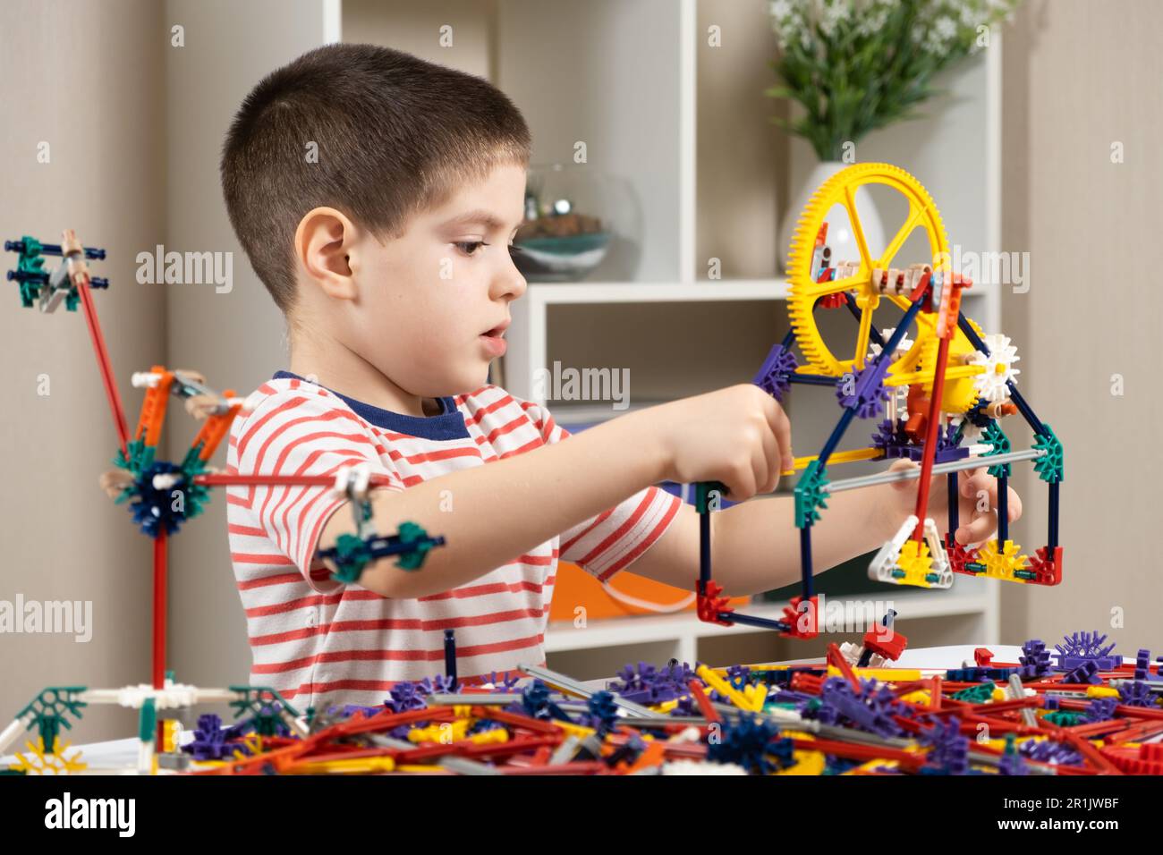 A little boy plays with a constructor, creating figures from gears and ...