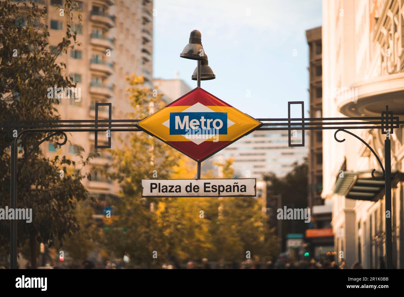 A vivid color image of a city street featuring a hanging metro sign ...