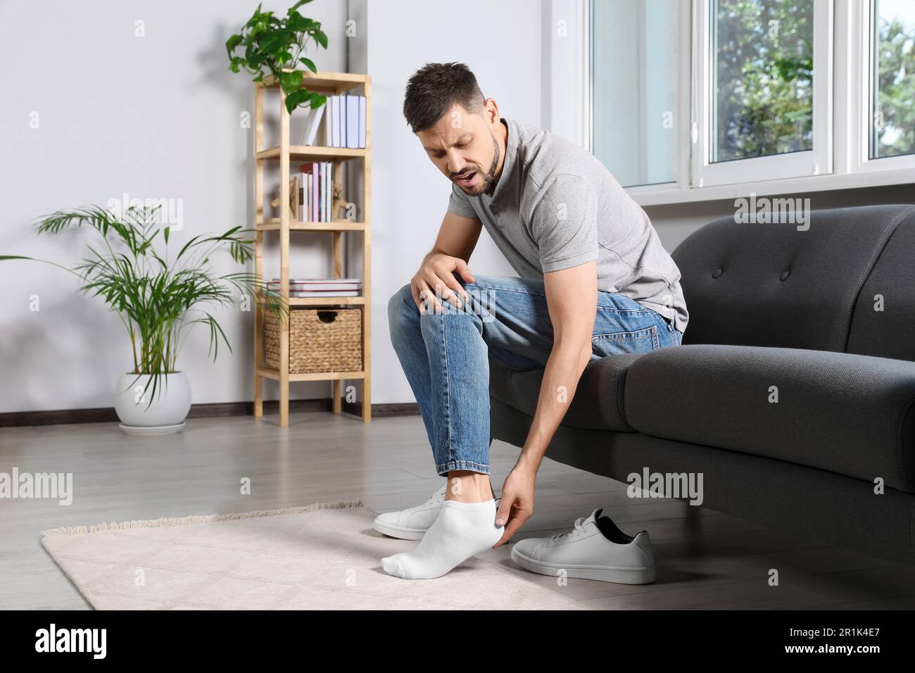 Man suffering from foot pain at home, space for text Stock Photo - Alamy