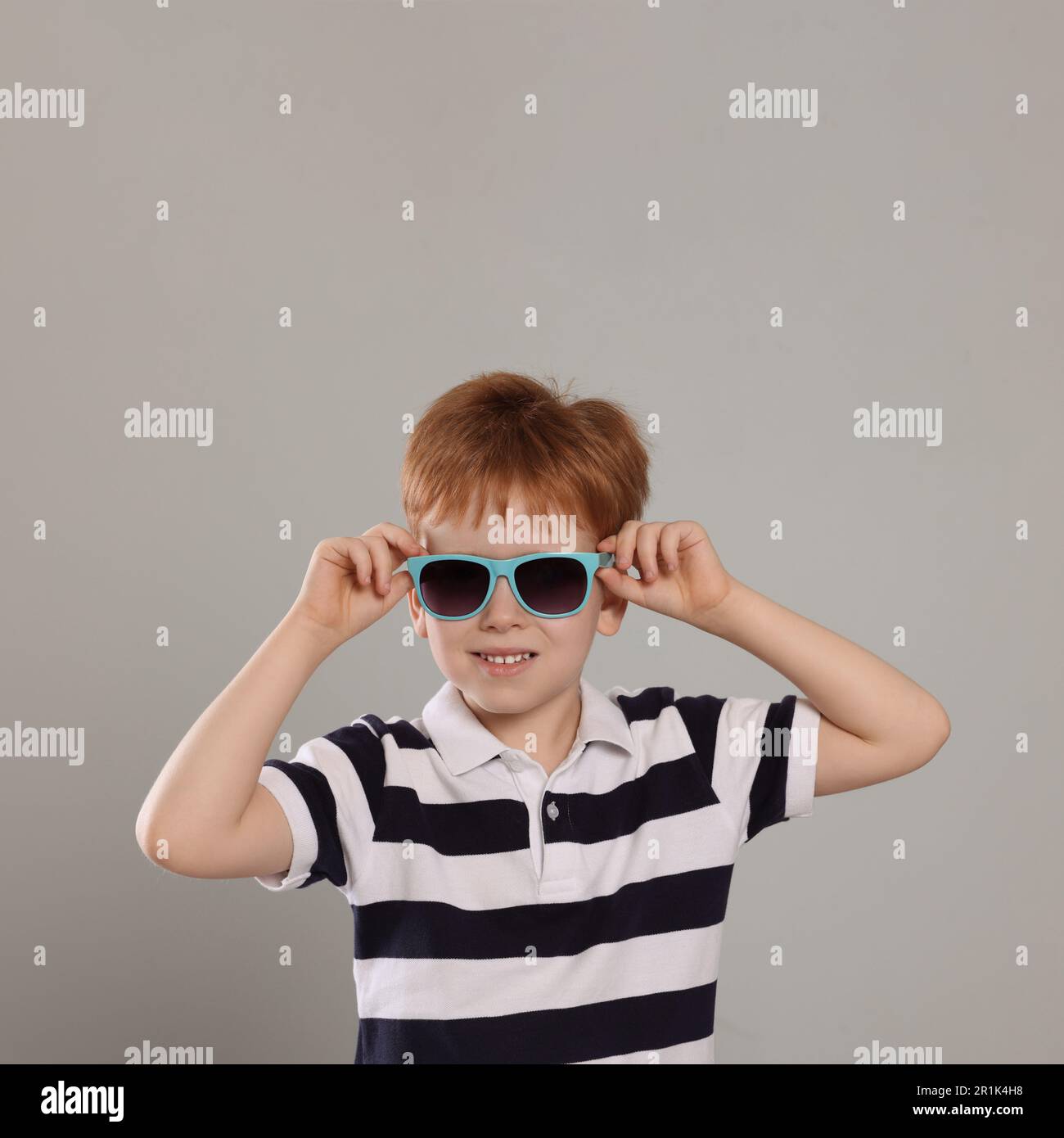 Cute little boy with sunglasses on light grey background Stock Photo ...
