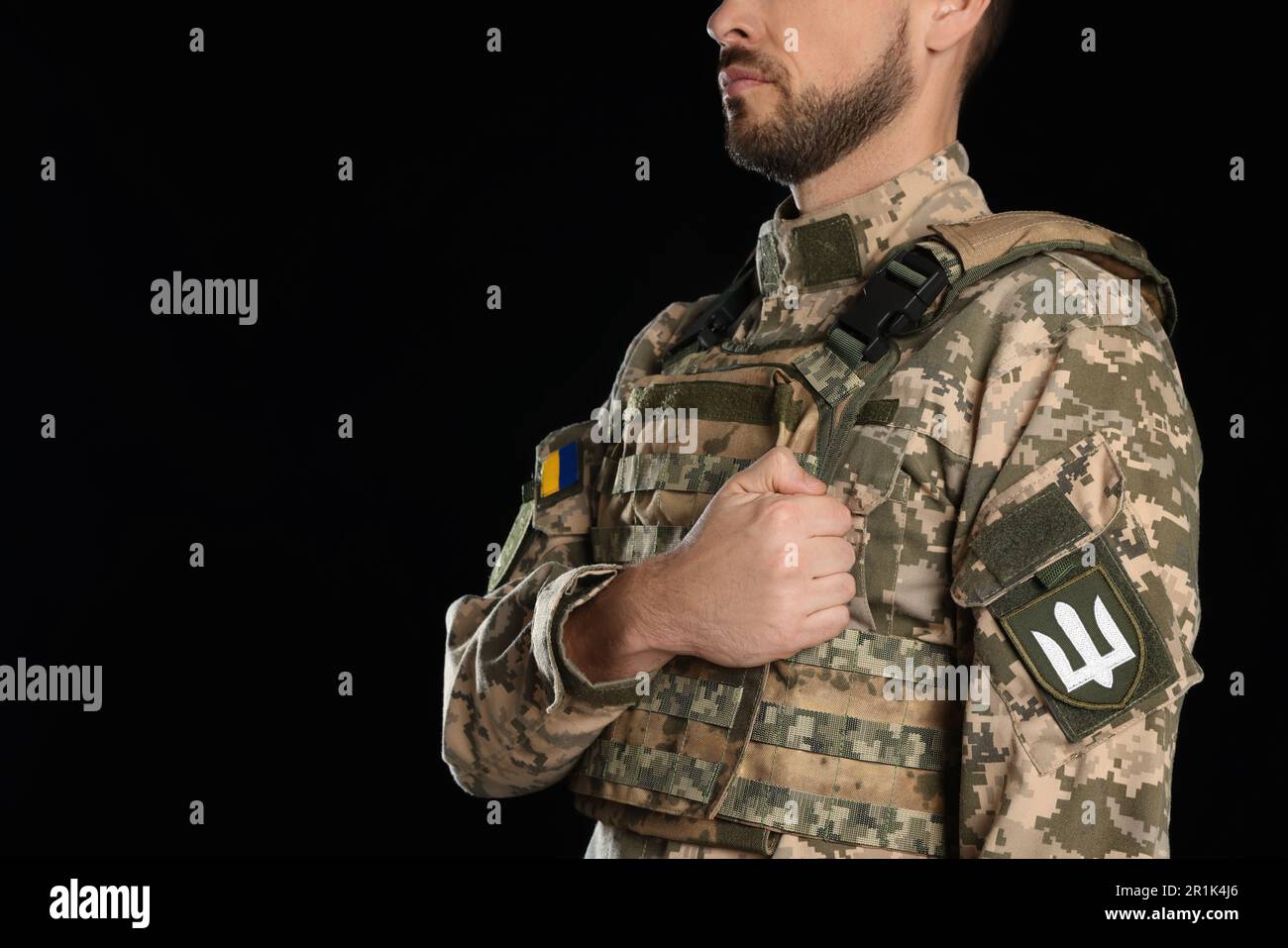 Soldier with Ukrainian trident on military uniform against black ...