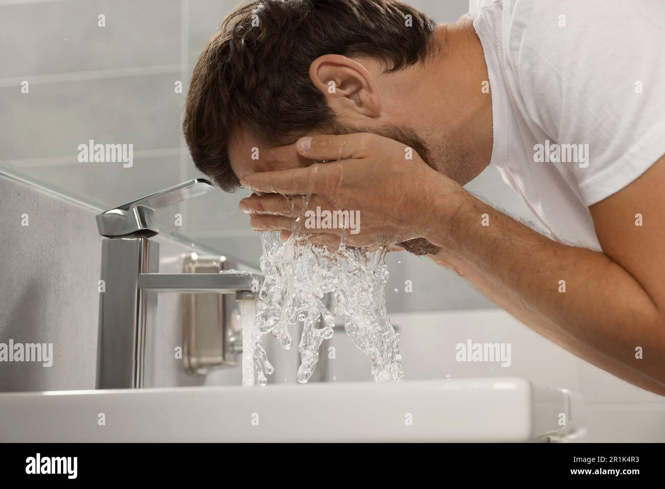 Handsome man washing face in bathroom, closeup Stock Photo - Alamy