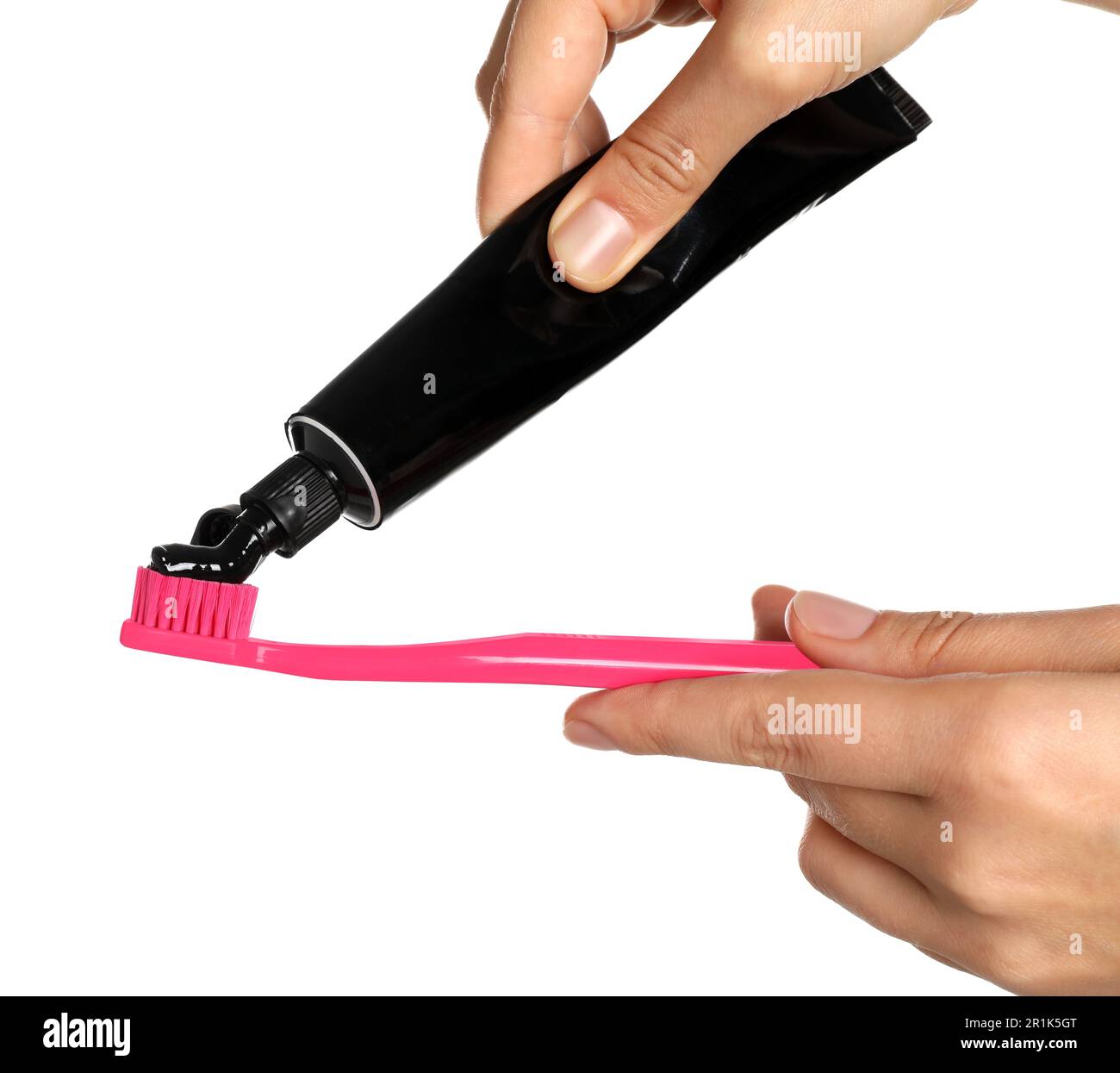 Woman applying charcoal toothpaste on brush against white background ...