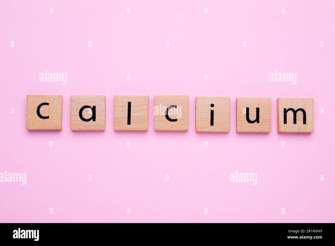 Word Calcium made of wooden cubes with letters on pale pink background ...