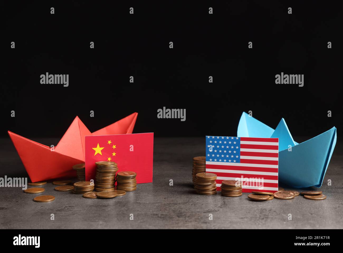 American and Chinese flags, coins with paper boats on grey table ...