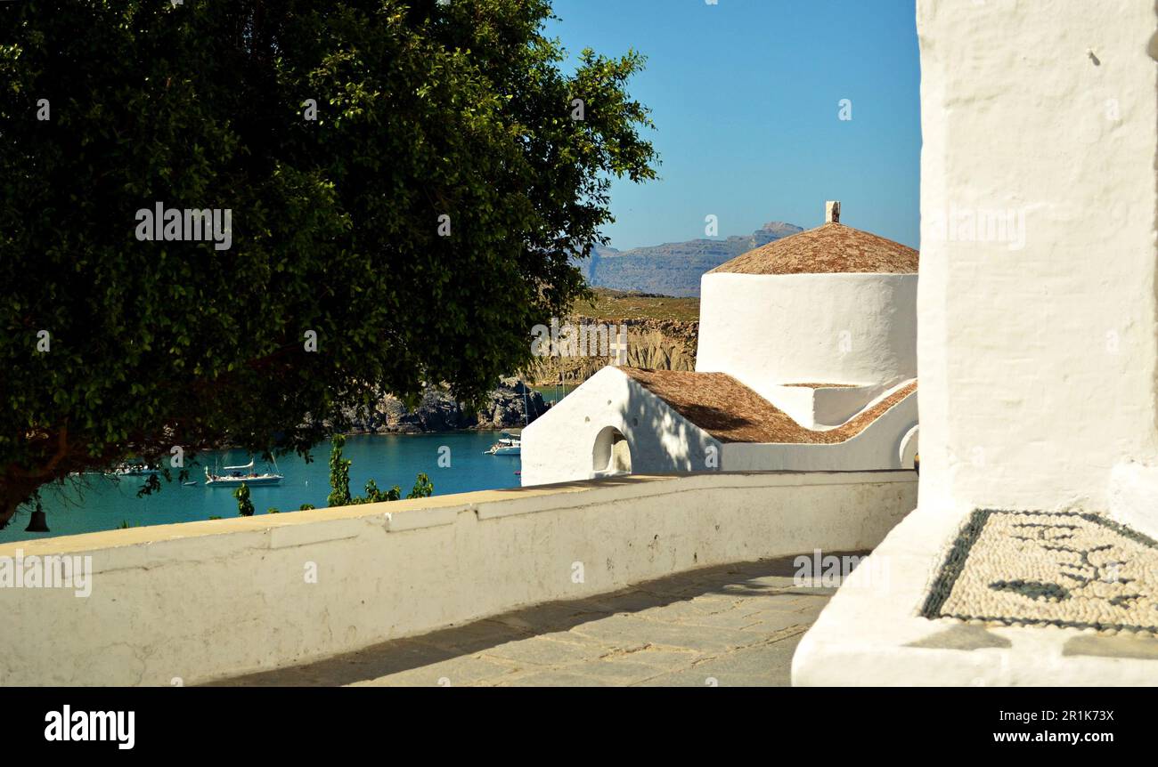 White Christian church in the Cycladic style on a narrow street in the village of Lindos.View of ...