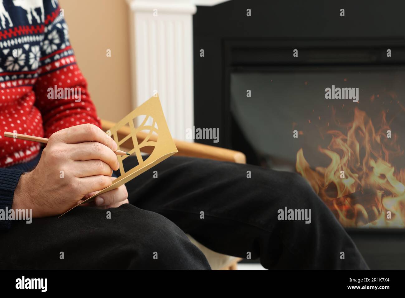 Man writing wishes in Christmas greeting card in living room, closeup ...