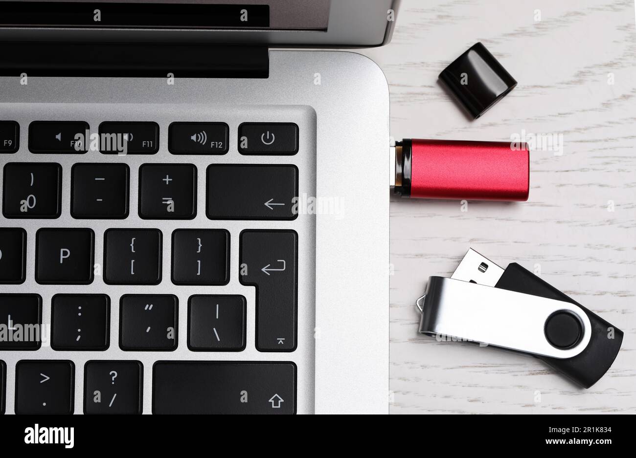 Modern usb flash drive attached into laptop on white wooden table, flat ...