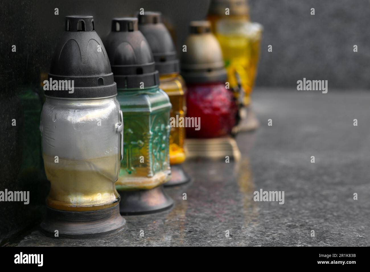 Different grave lanterns on granite tombstone outdoors, space for text Stock Photo - Alamy