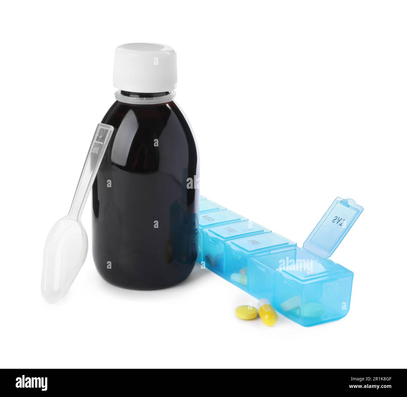 Bottle of syrup, plastic spoon with pills on white background. Cough ...