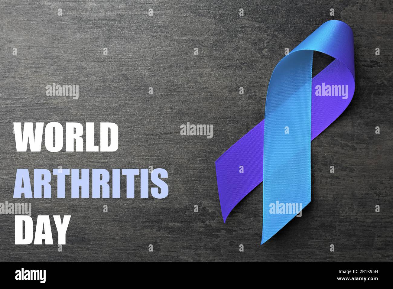 World Arthritis Day. Blue and purple awareness ribbon on dark grey ...