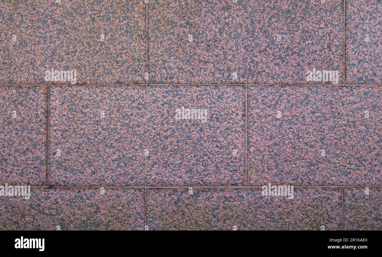 Close-up of a wall made of natural red granite rock blocks, front view ...