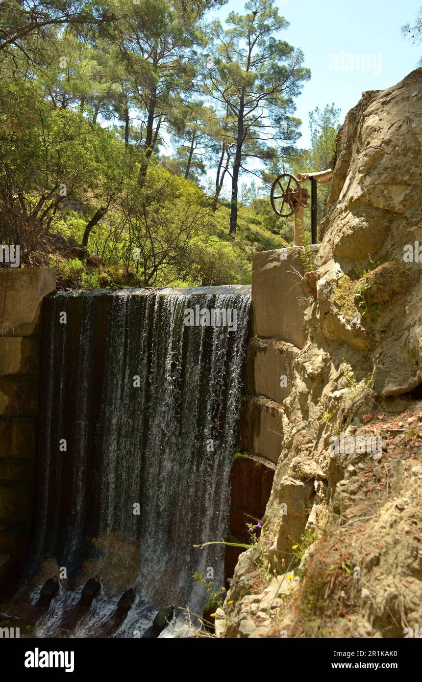 An artificial waterfall among the tall trees of the nature reserve on ...