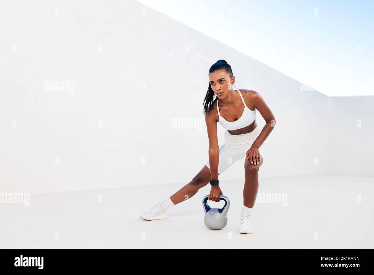 Full length of slim woman exercising with kettlebell outdoors ...